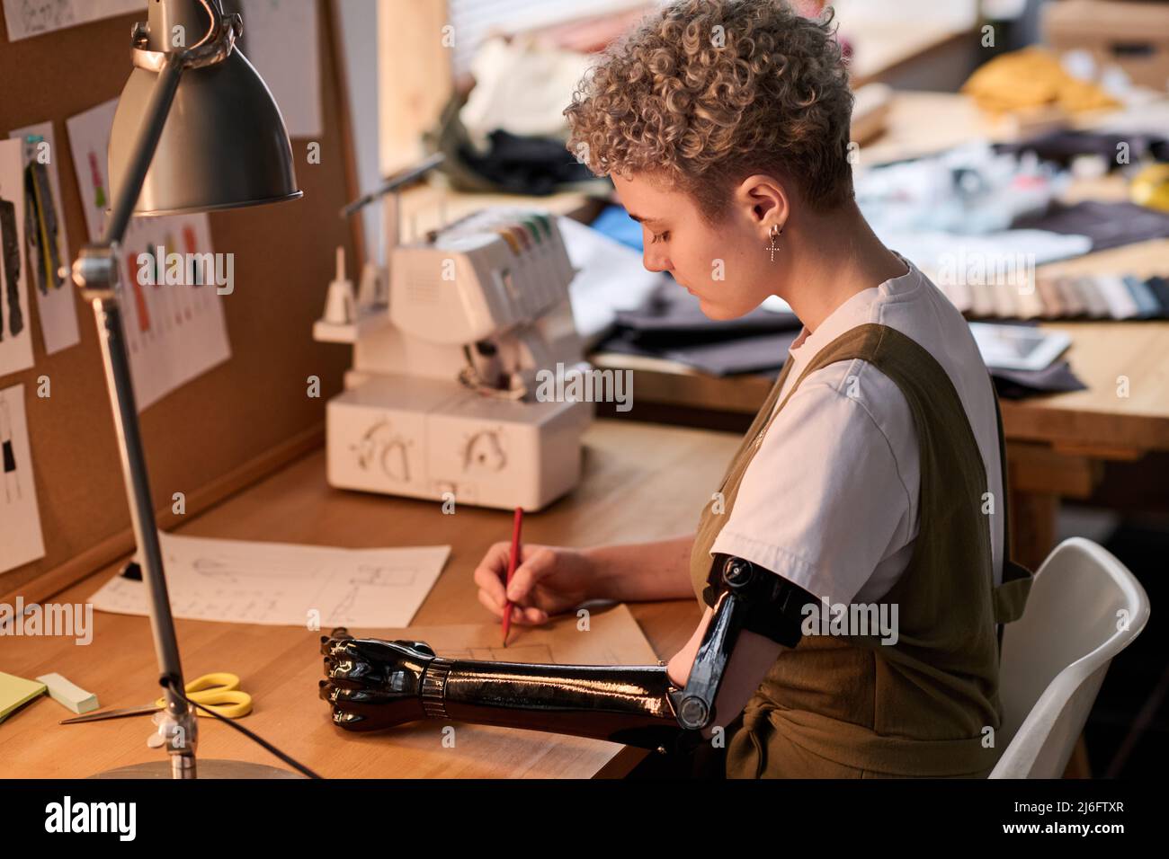 Young contemporary fashion designer drawing new sketches in notepad ...