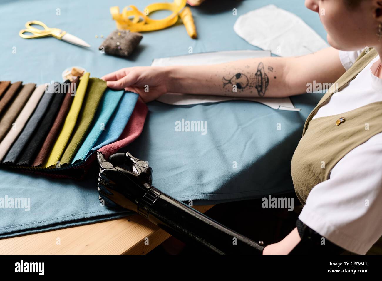 Contemporary young female clothes designer choosing fabric samples by ...
