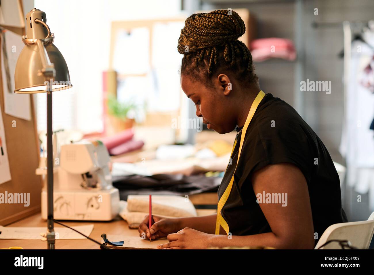 Side view of young creative seamstress with pencil drawing sketch of ...