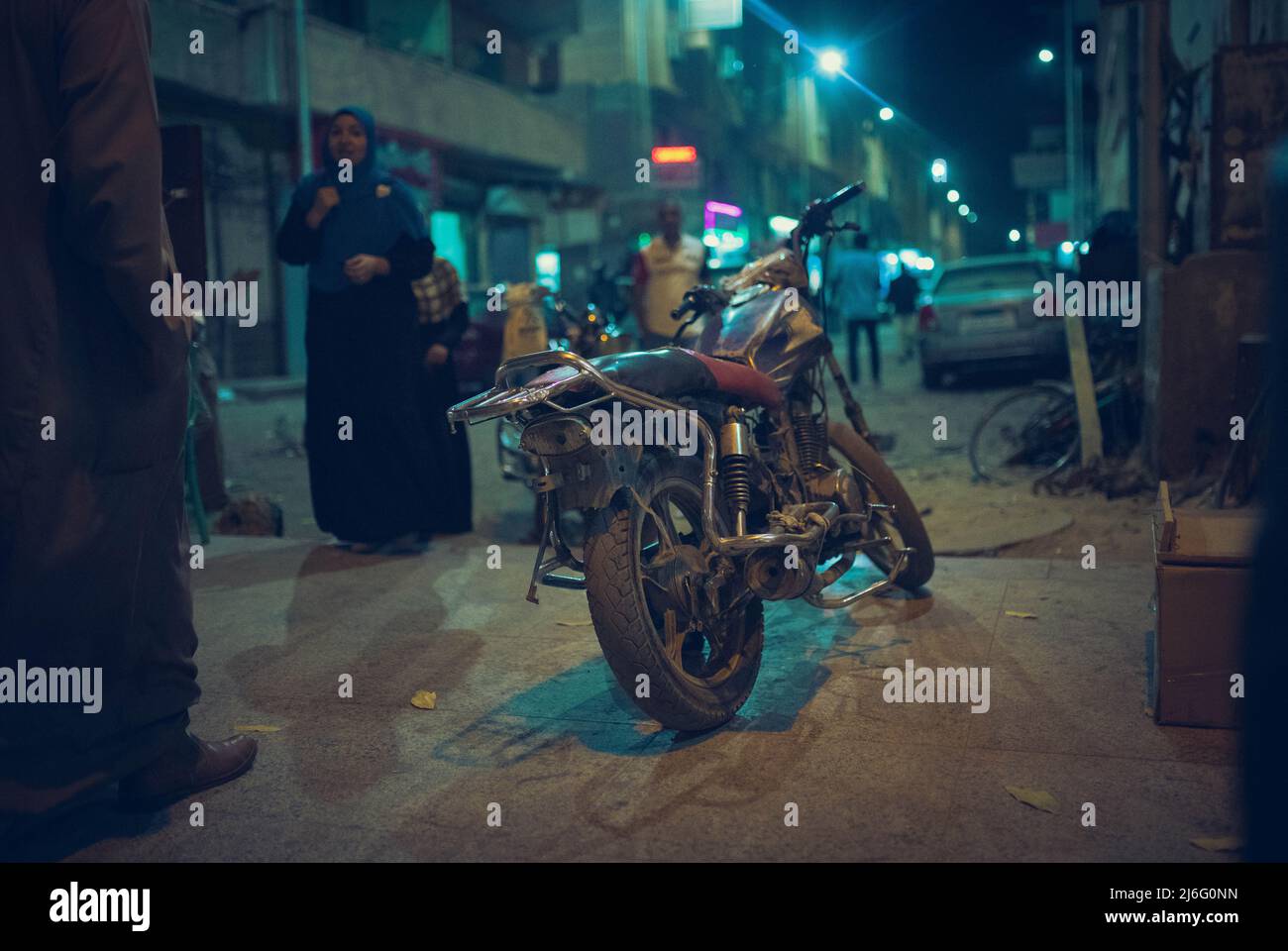 A motorbike in Aswan, Egypt at night lights and an arabic woman walking ...