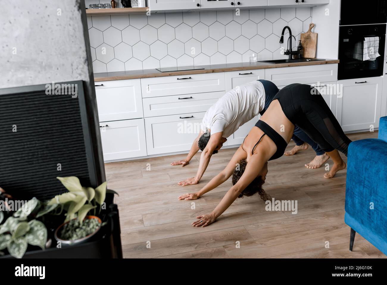 Couple exercising together on the modern kitchen floor. Man and woman in sports wear doing ...