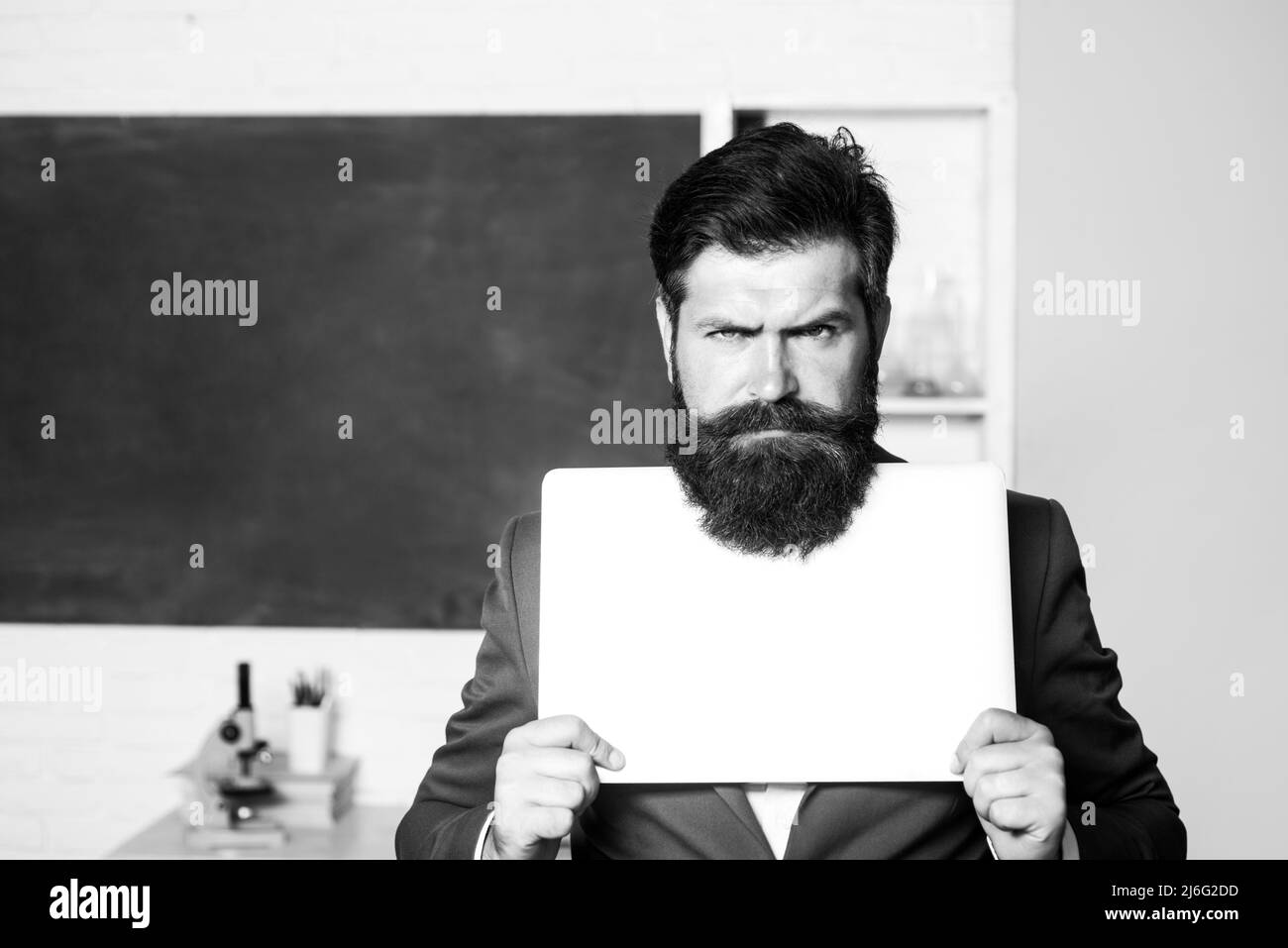 Serious teacher holding laptop, teacher bearded professor with ...