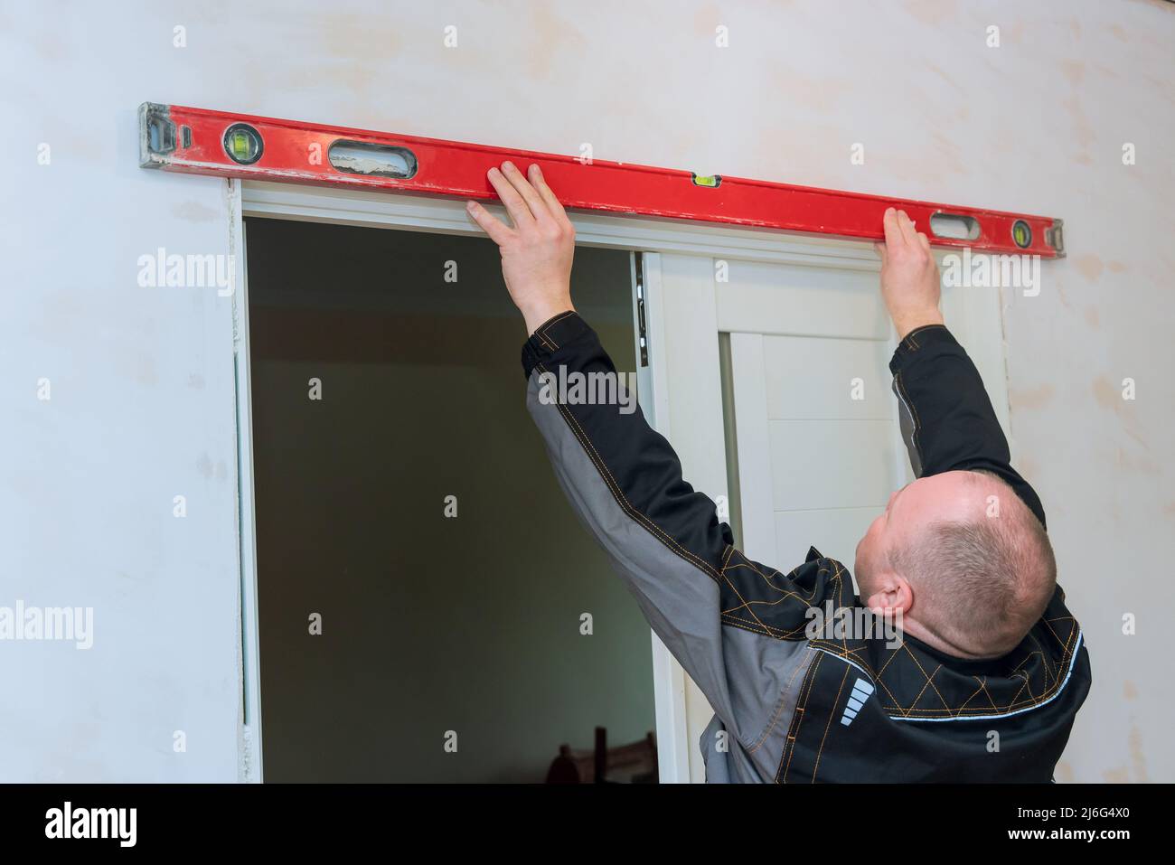 Carpenter at interior wood door installation working with level Stock ...