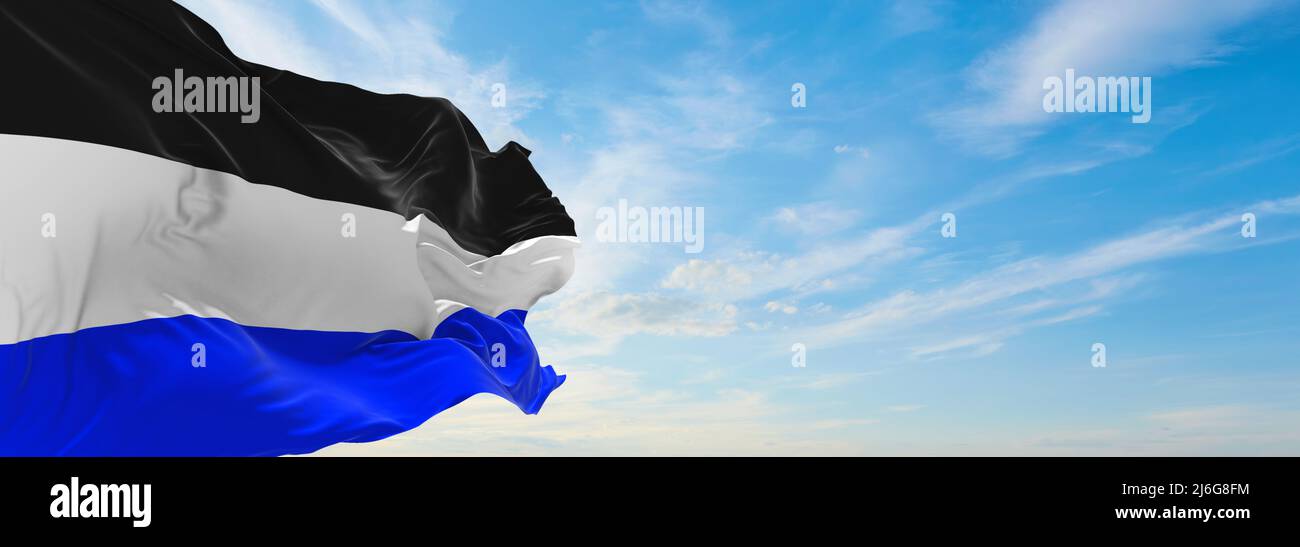 official flag of Moresnet, Belgium at cloudy sky background on sunset ...