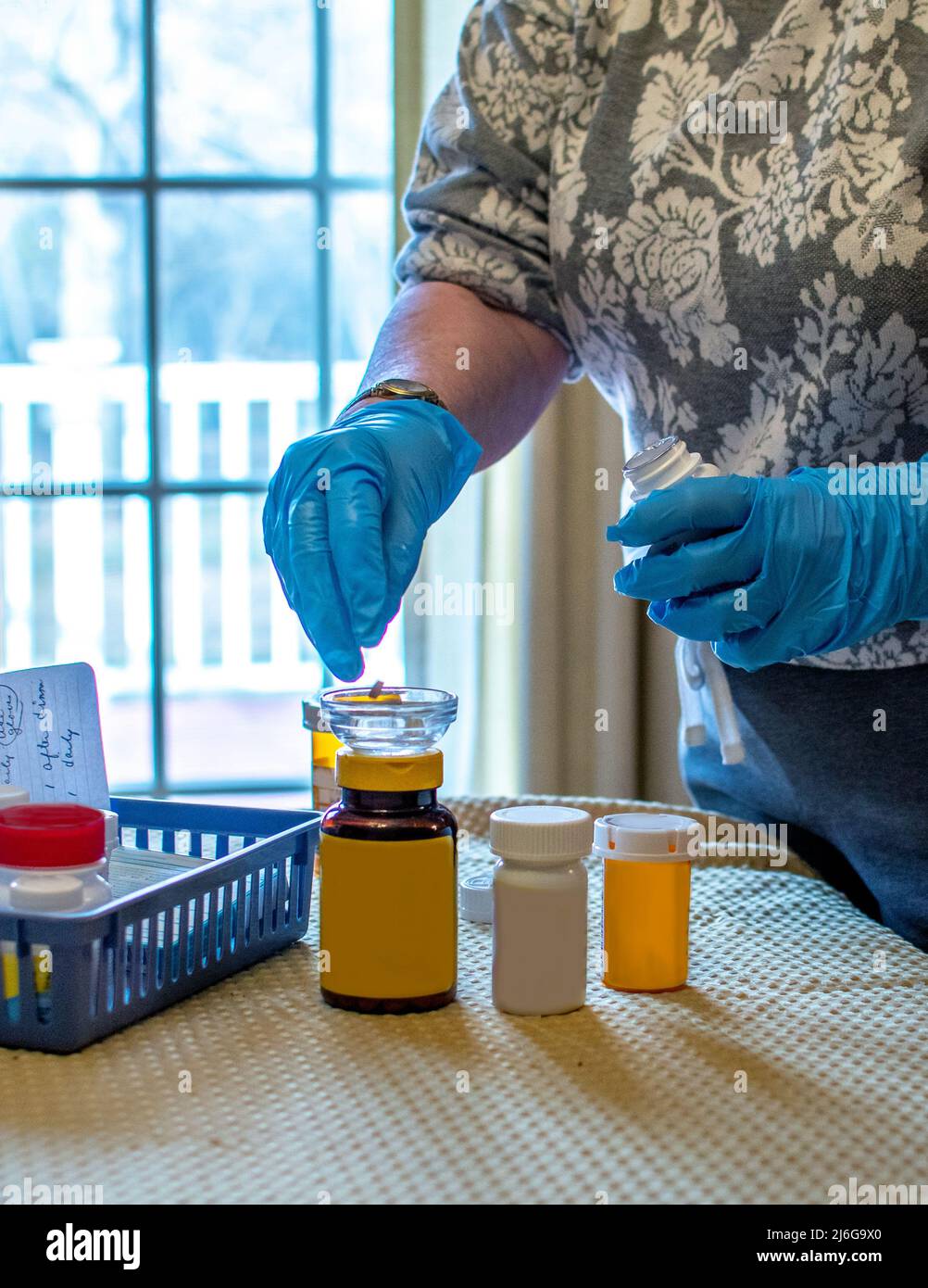 woman wearing gloves for safety, prepares a serving of medication for ...