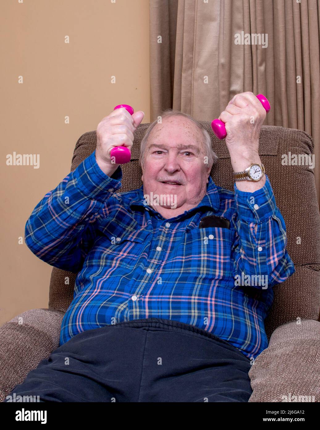 smiling man exercises with small barbells from the comfort of his ...