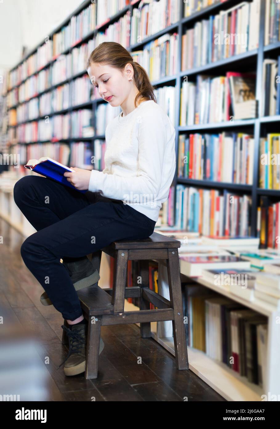 Girl reading book in bookshop Stock Photo - Alamy