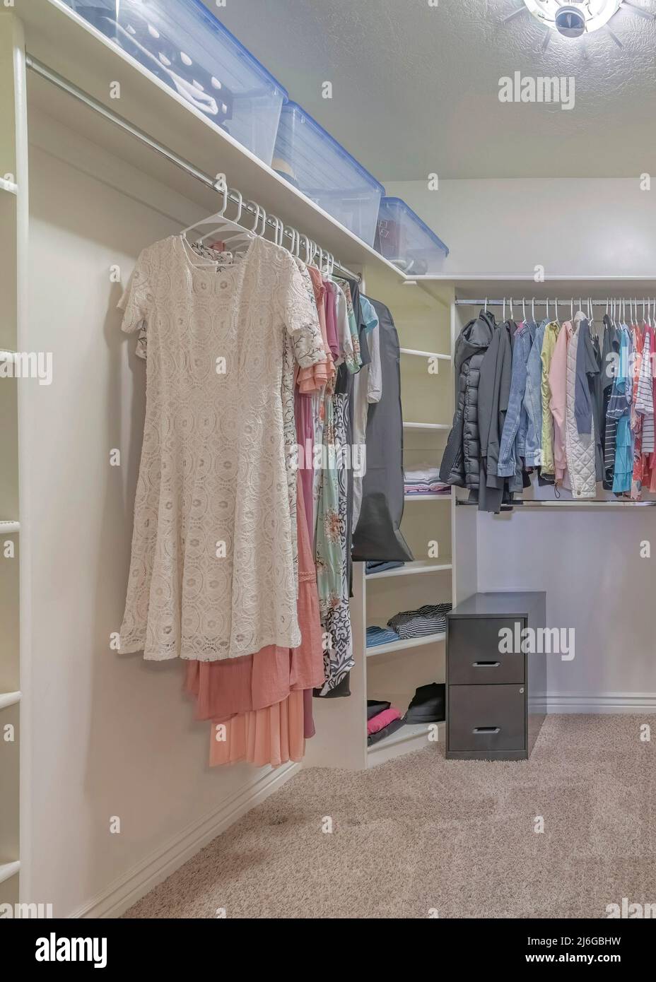 Vertical Interior of a walk in closet with shelving units and clothes ...