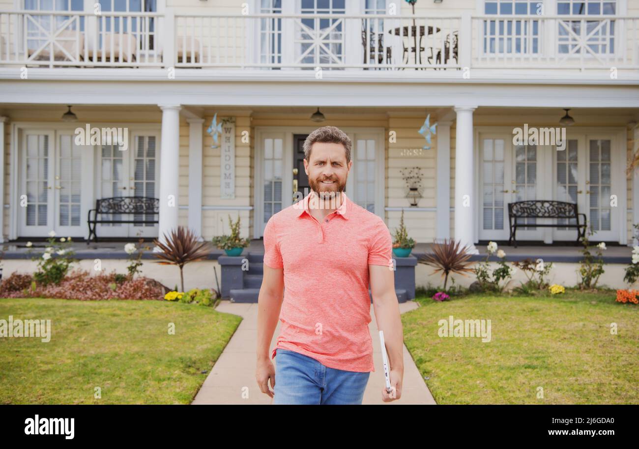 Portrait of confident real estate agent standing outside a house for ...