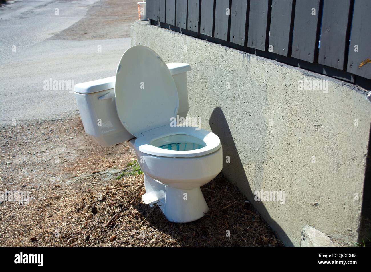 Toilet bowl sitting outside beside garbage area Stock Photo - Alamy