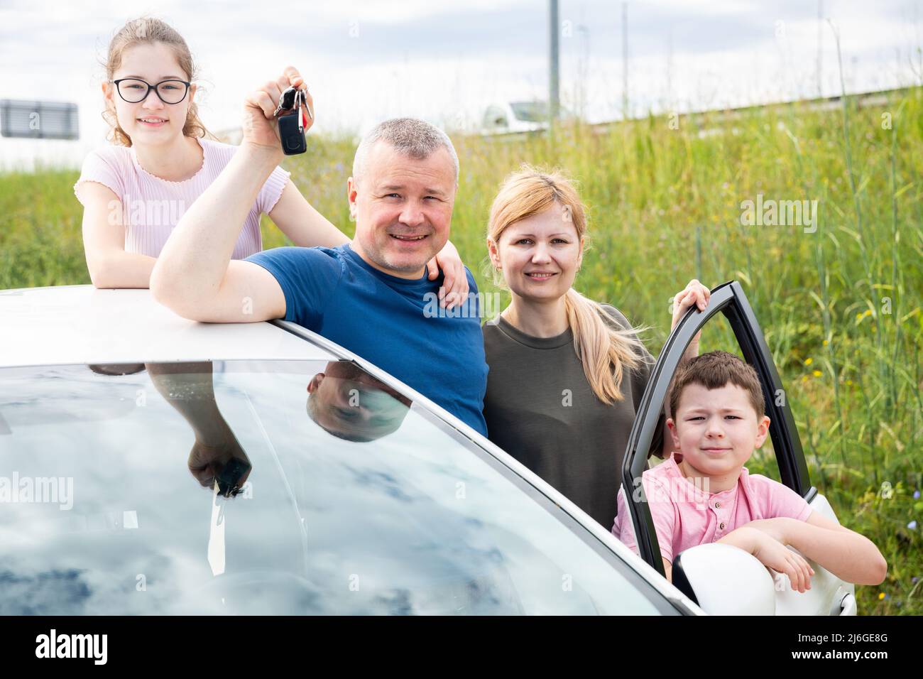 Happy parents with children posing together near car Stock Photo - Alamy