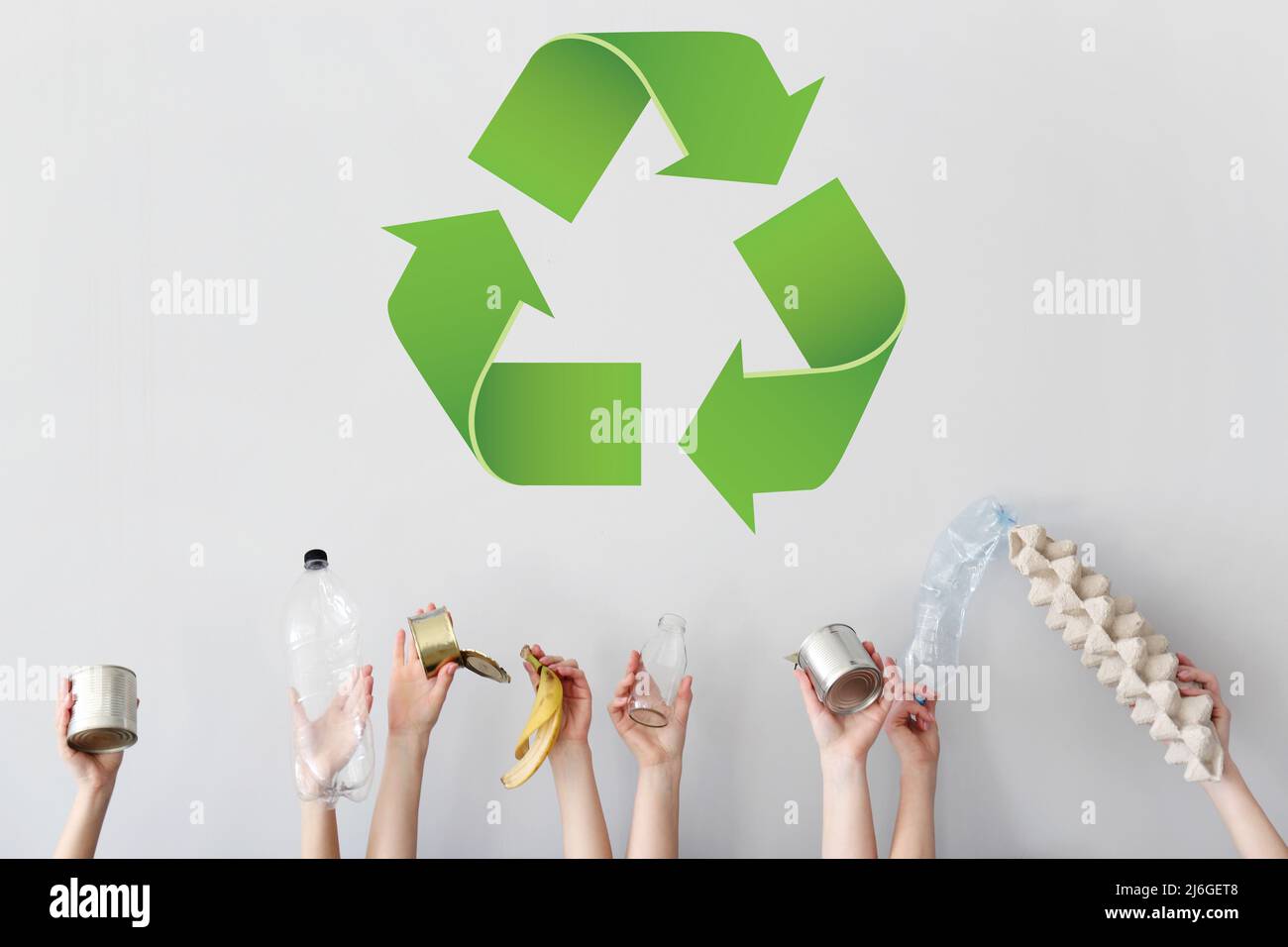 Hands with different types of garbage and recycling sign on light ...