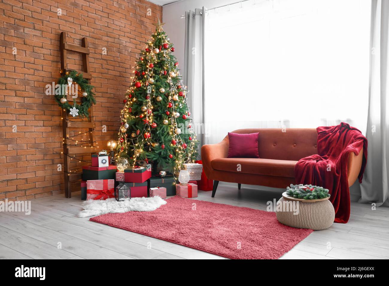 Christmas tree with presents and comfortable sofa with red carpet in ...