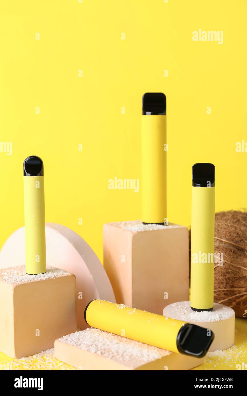 Disposable electronic cigarettes and coconut on yellow background Stock ...