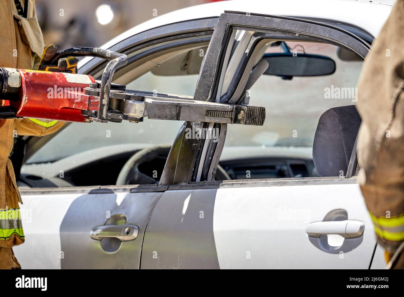 Close up of a fire fighter holding jaws of life while it crushes a car ...