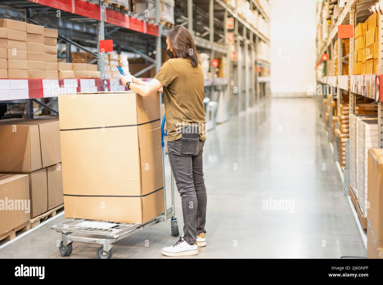 The Back view of the man using the mobile phone to check the price of ...