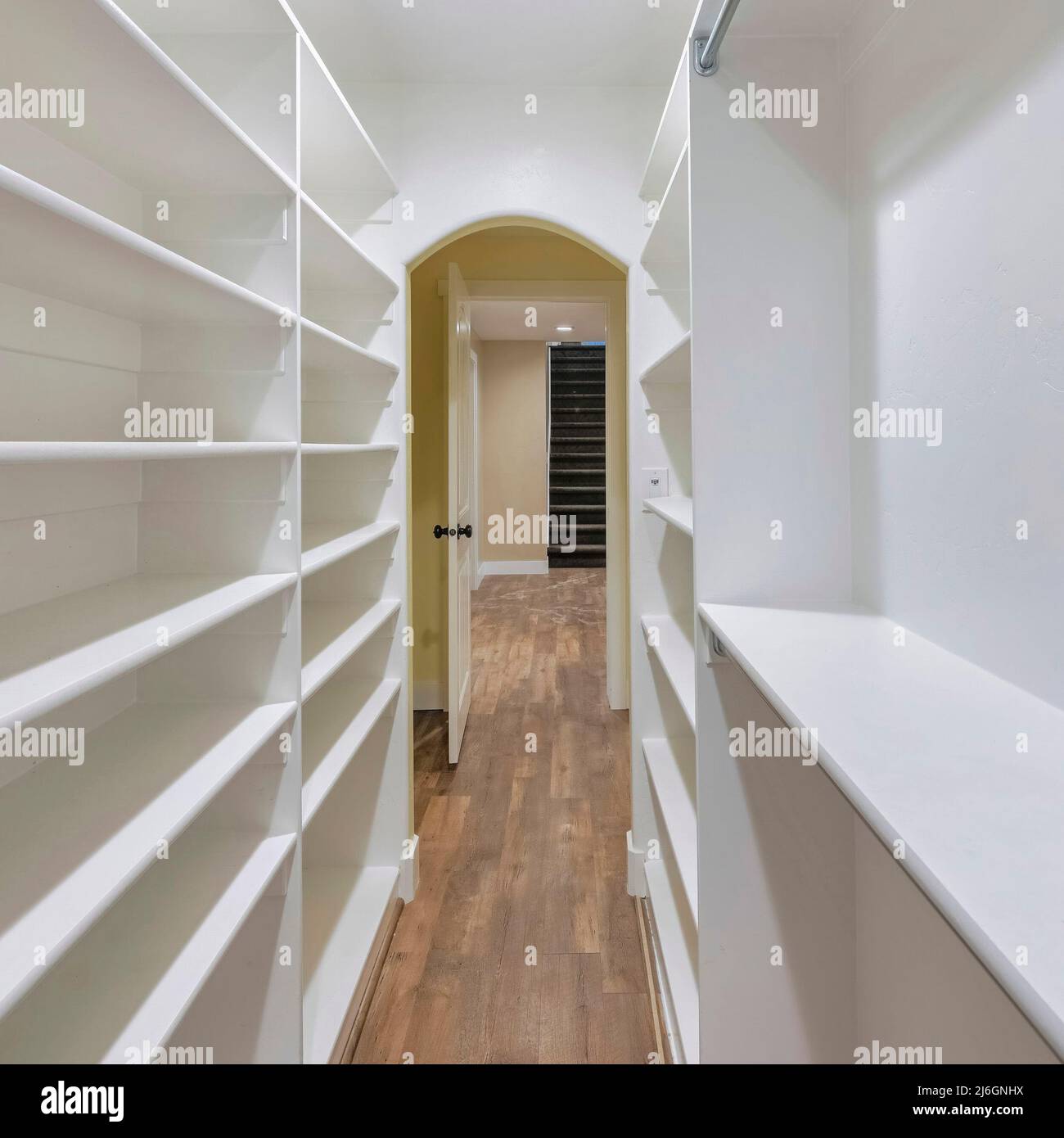 Square Narrow walk in closet with wood flooring and shelving units ...