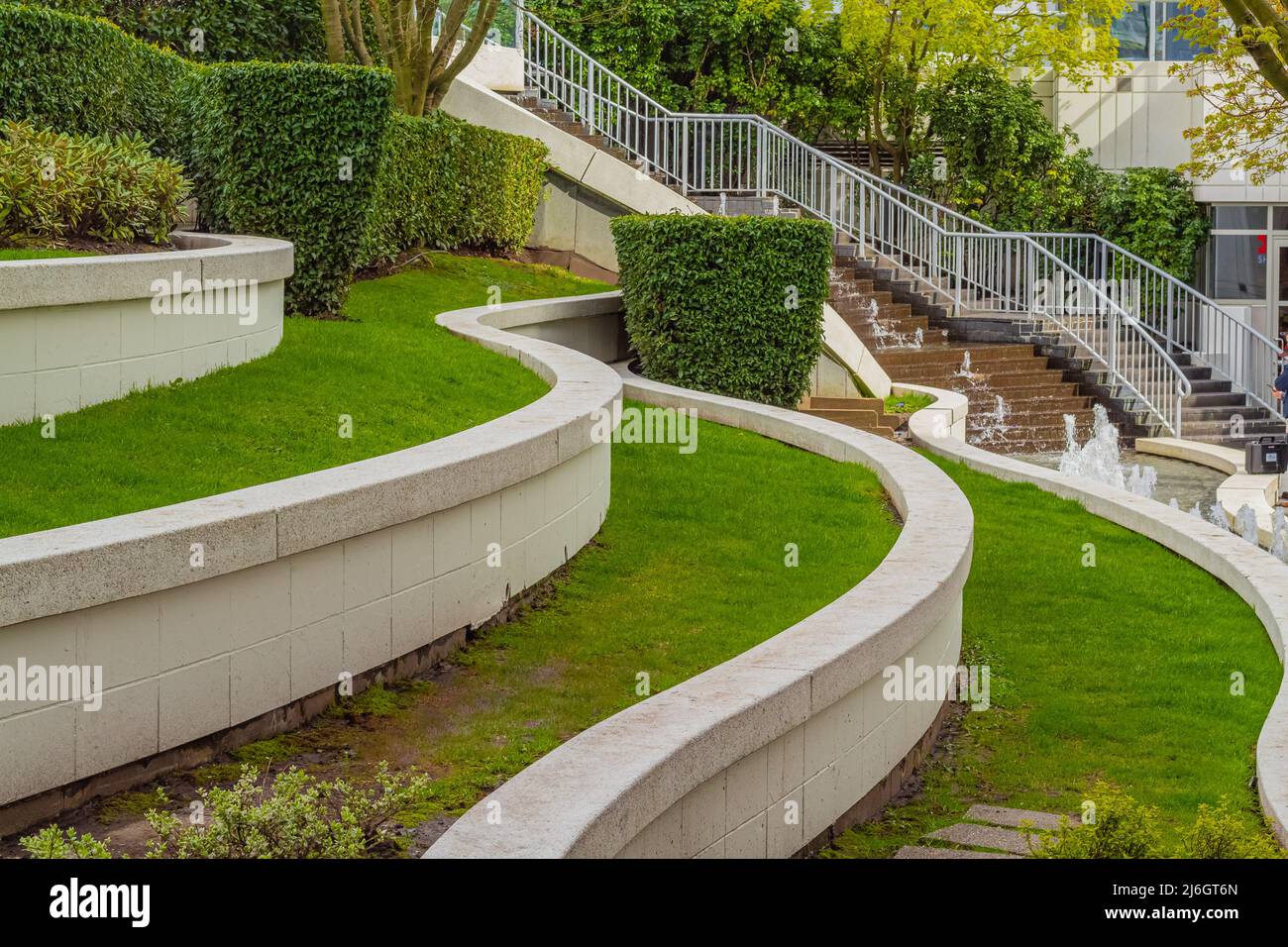 Leveled terraces with grass and fountains in a city plaza, business ...