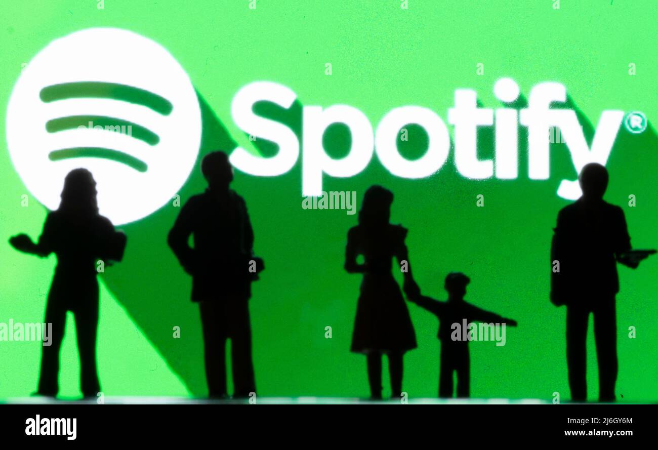 Miniature figures standing in front of a blurred Spotify logo on the ...