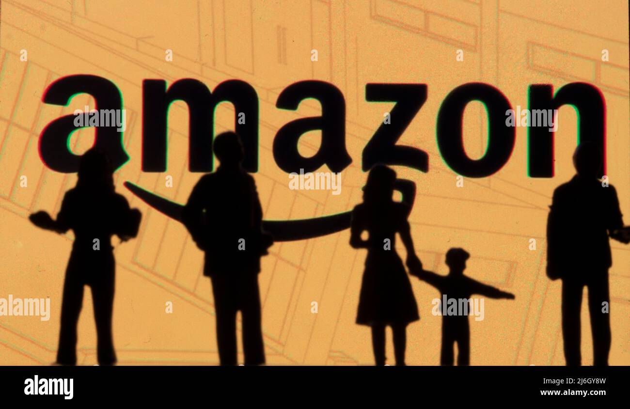Miniature figures standing in front of a blurred Amazon logo on the ...