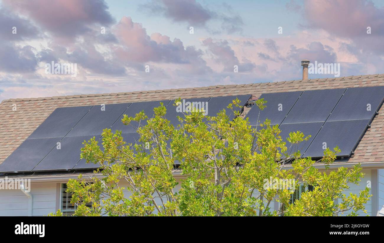 Panorama Puffy clouds at sunset Solar panels on the shingles roof of a ...