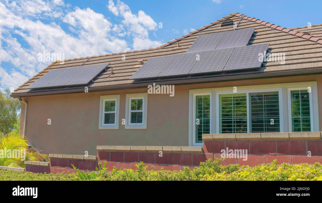 Panorama White puffy clouds Exterior of a light brown house with solar ...