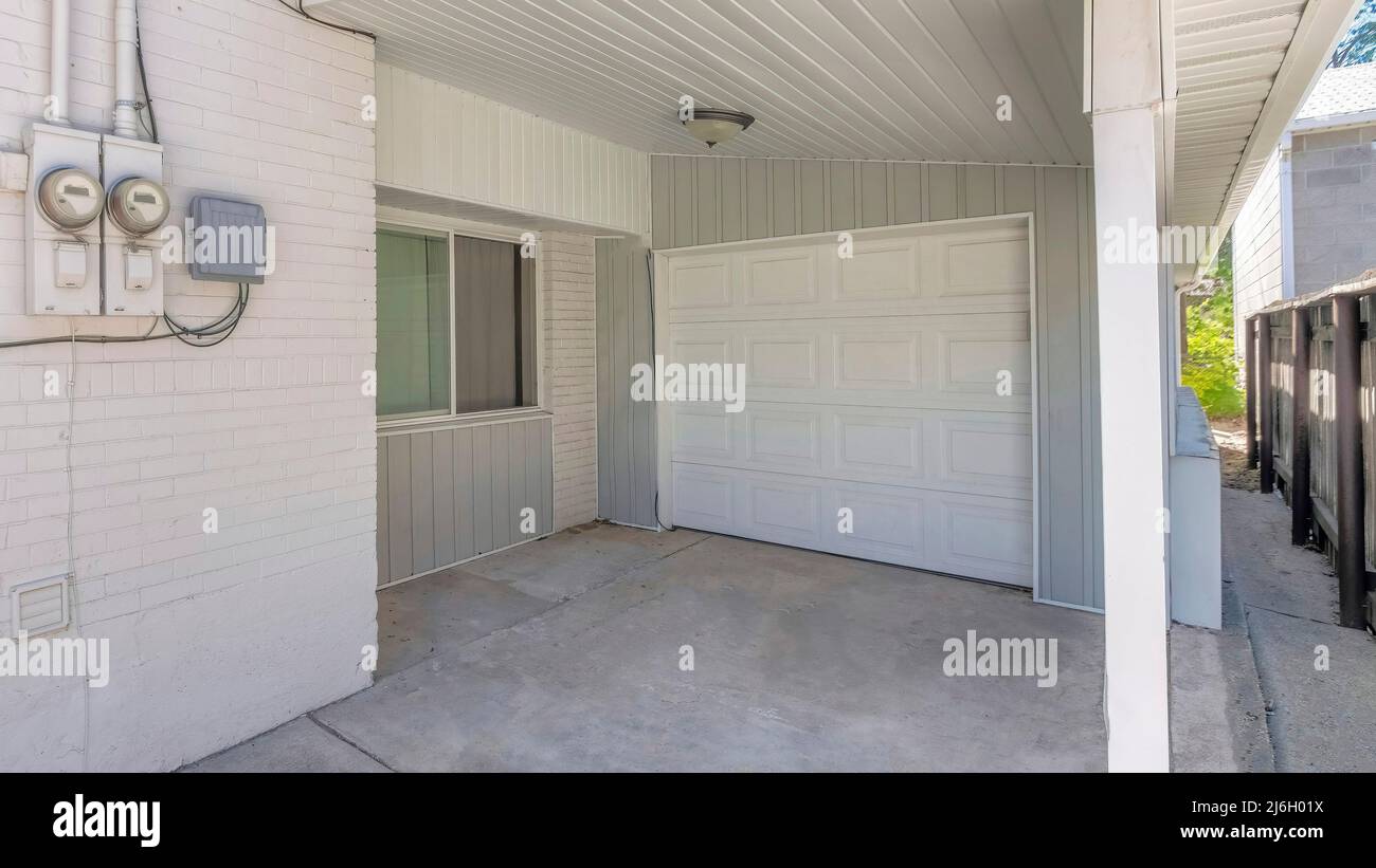 Panorama Small garage at the side of a house with white siding and two ...