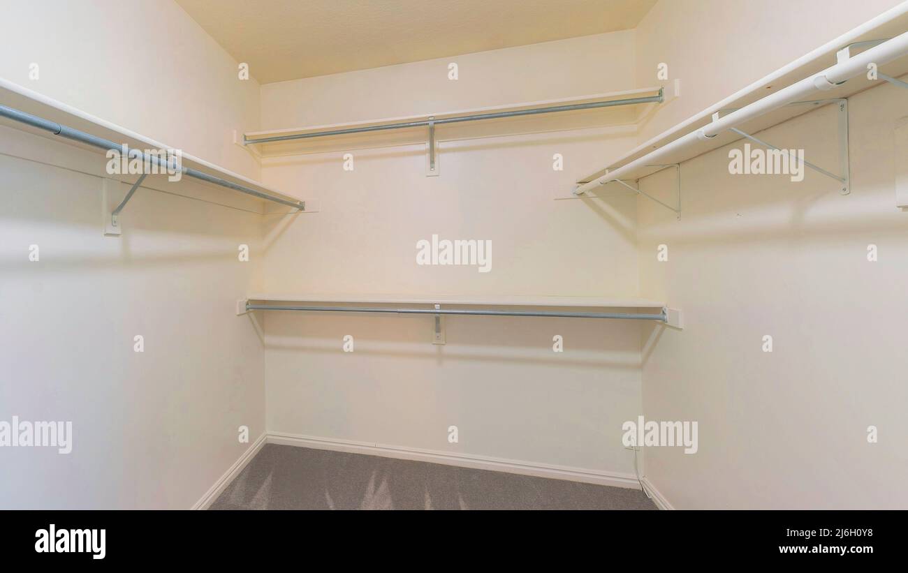 Panorama Empty walk in closet with gray carpet flooring and shelving ...