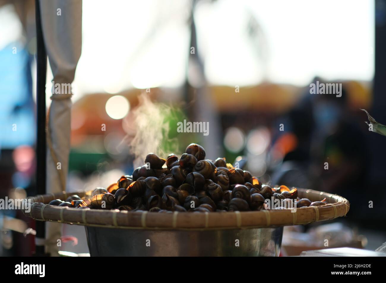 A heap of just boiled mollusks on a tray, with steam rising in a ...