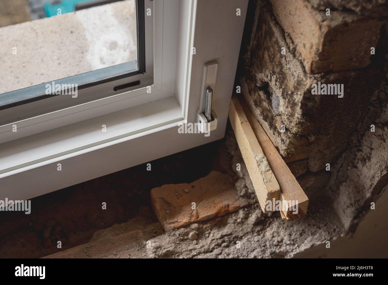 Two wooden chocks or drifts are used to position the new window in an ...