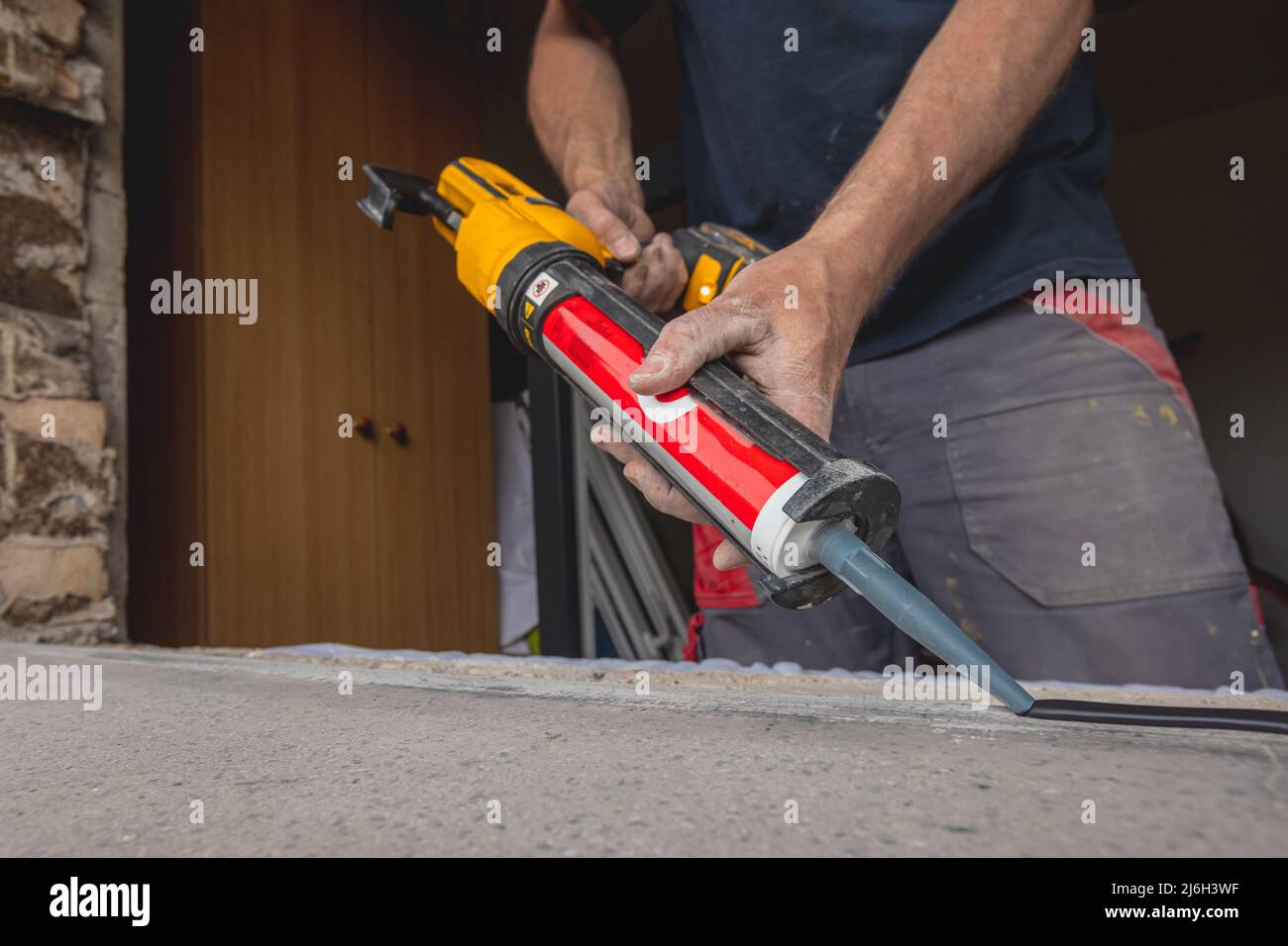 Modern window instalation in an old house. Worker applying sealant or ...
