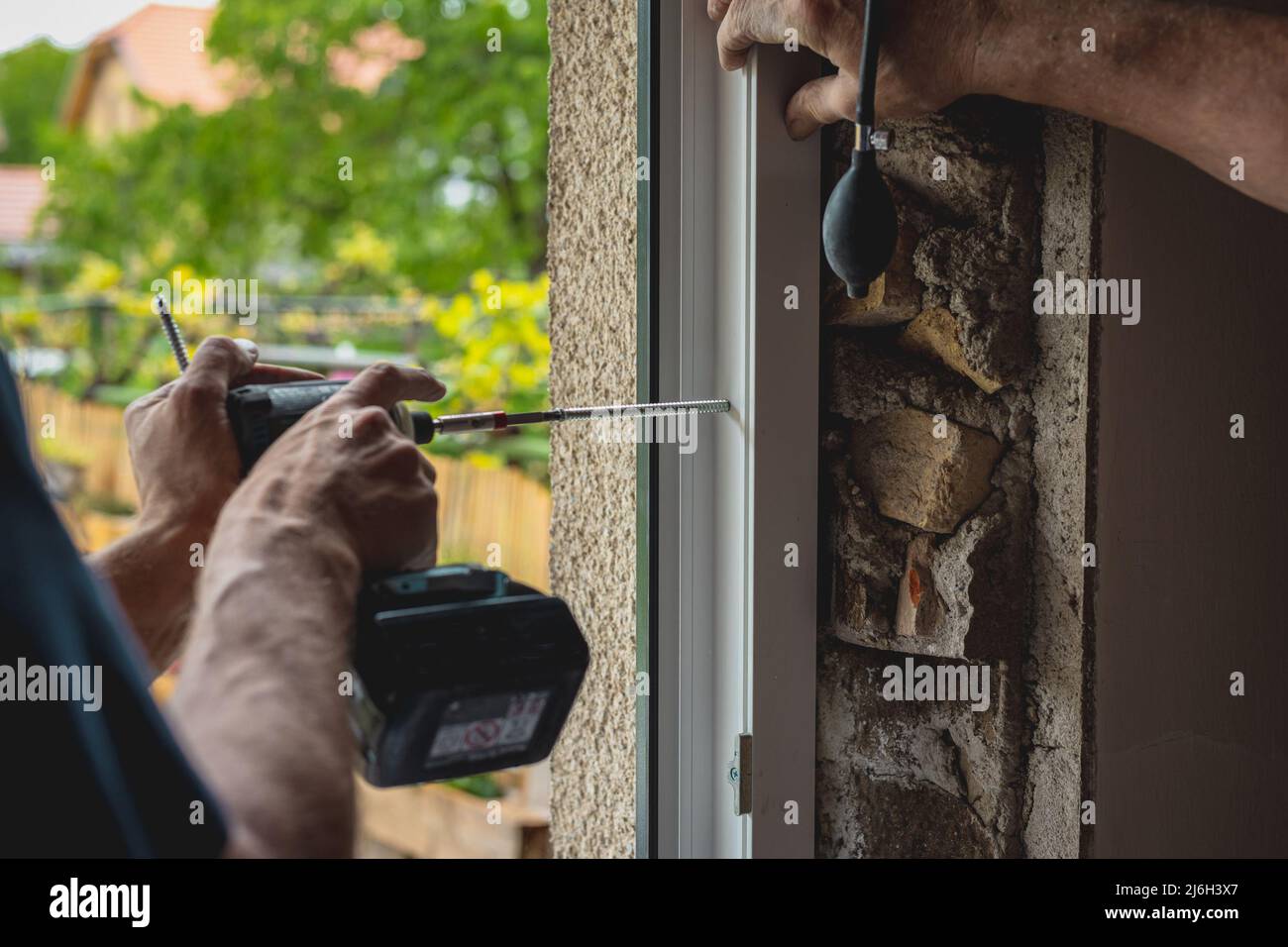 Person using a battery powered drill to install modern pvc windows or ...