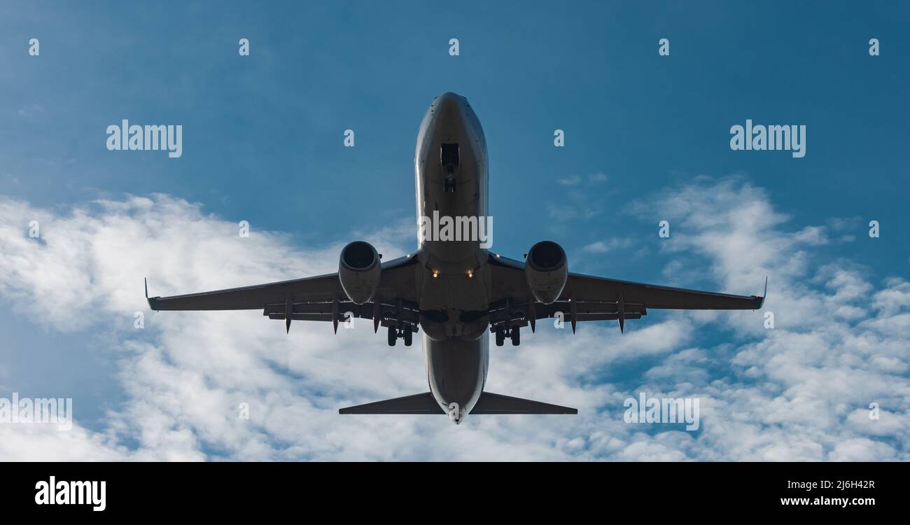 Frontal view of modern twin jet engine descending from the clouds. Low ...