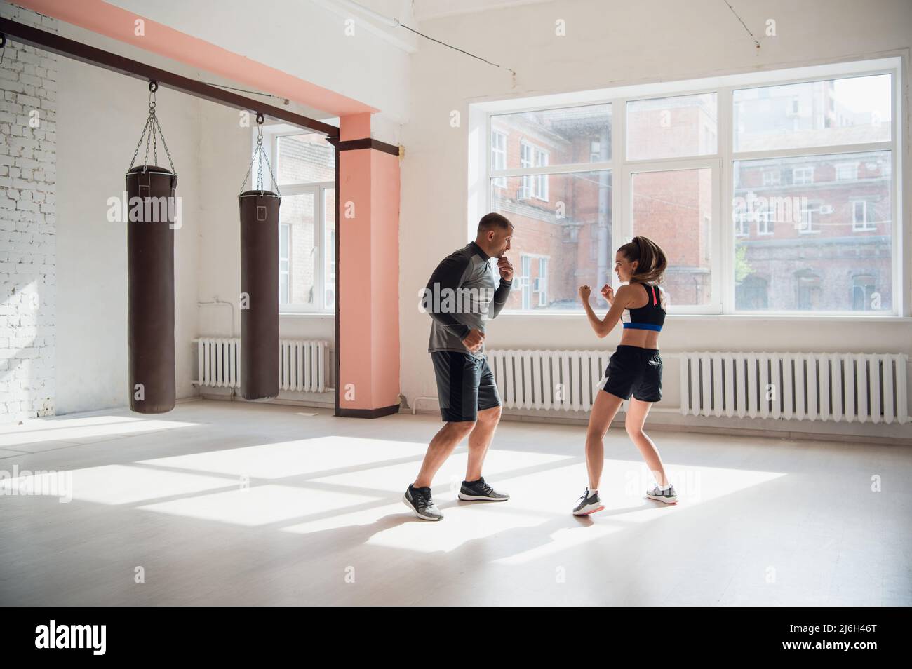 An attractive young boxer teaches his girlfriend boxing techniques in a ...