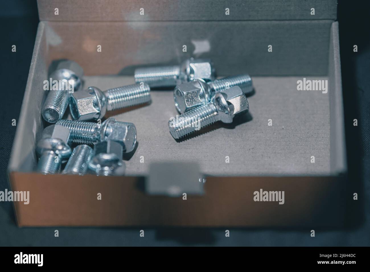 Automotive screws or set of wheel screws lying in a cardboard box ...