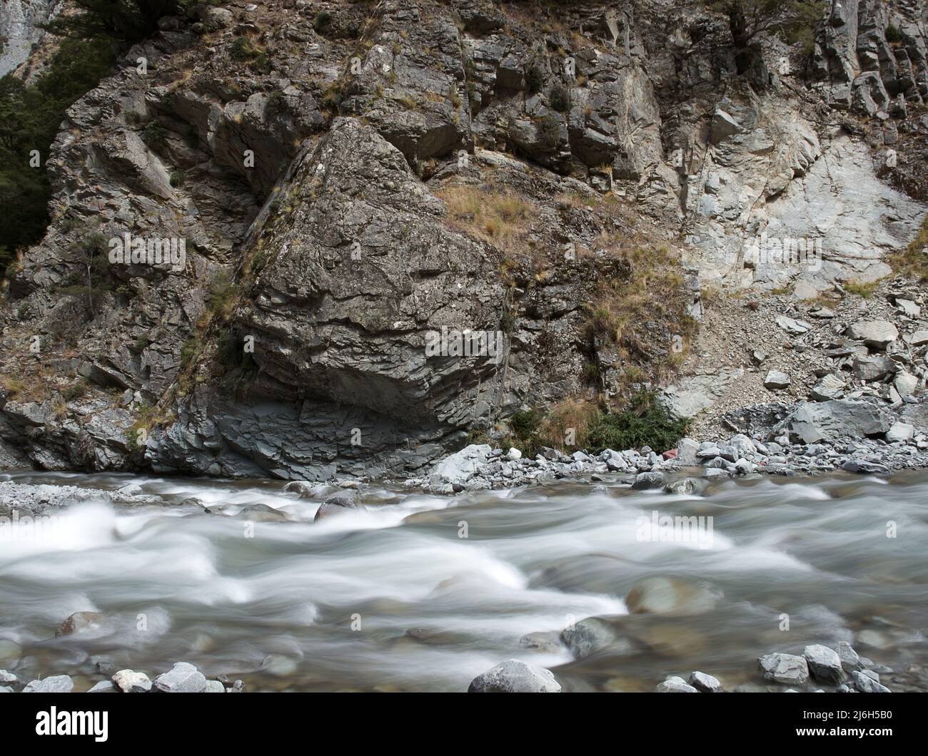A river flows below a rocky cliff, New Zealand Stock Photo - Alamy