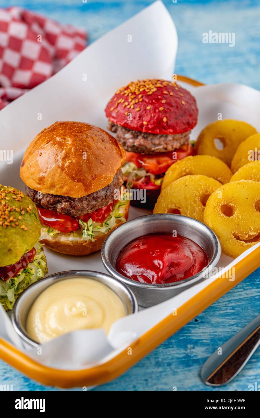 three mini burgers with chicken and meat served with french fries. kids ...