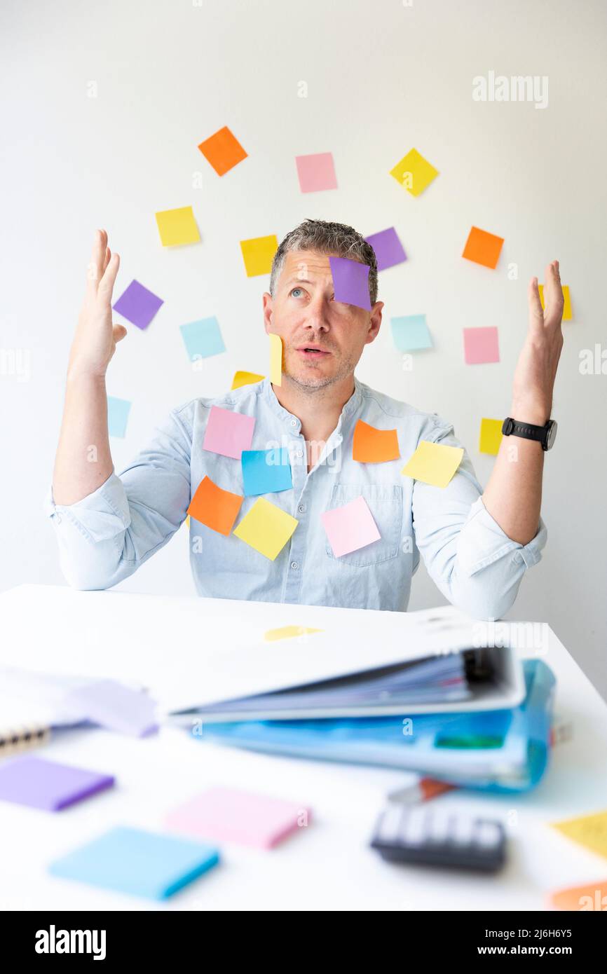 Man sits behind white office desk in front of wall with many colorful ...