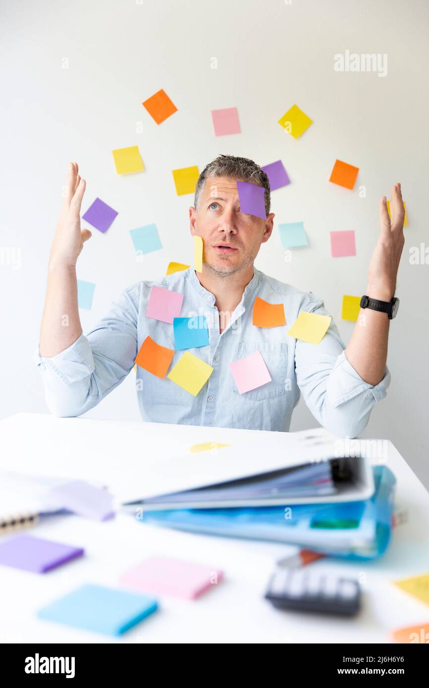 Man sits behind white office desk in front of wall with many colorful ...
