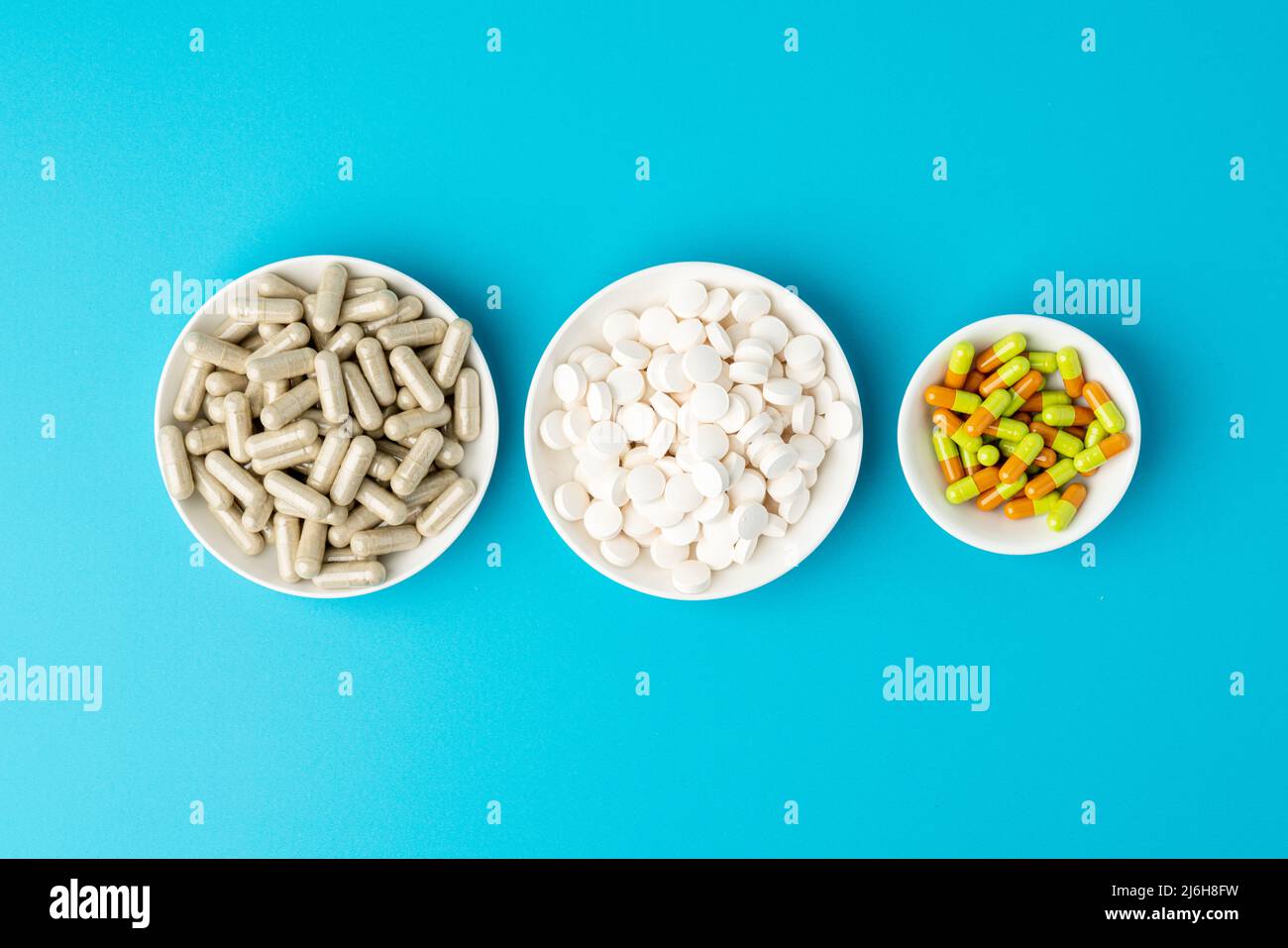 Turquoise background of large group of assorted capsules, pills and ...