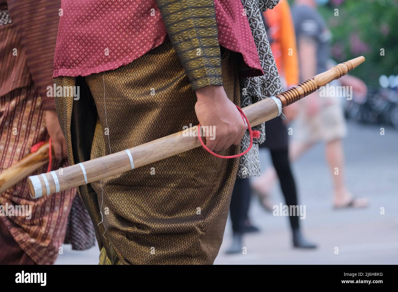 A Thai man is wearing a traditional suit and holding a traditional ...