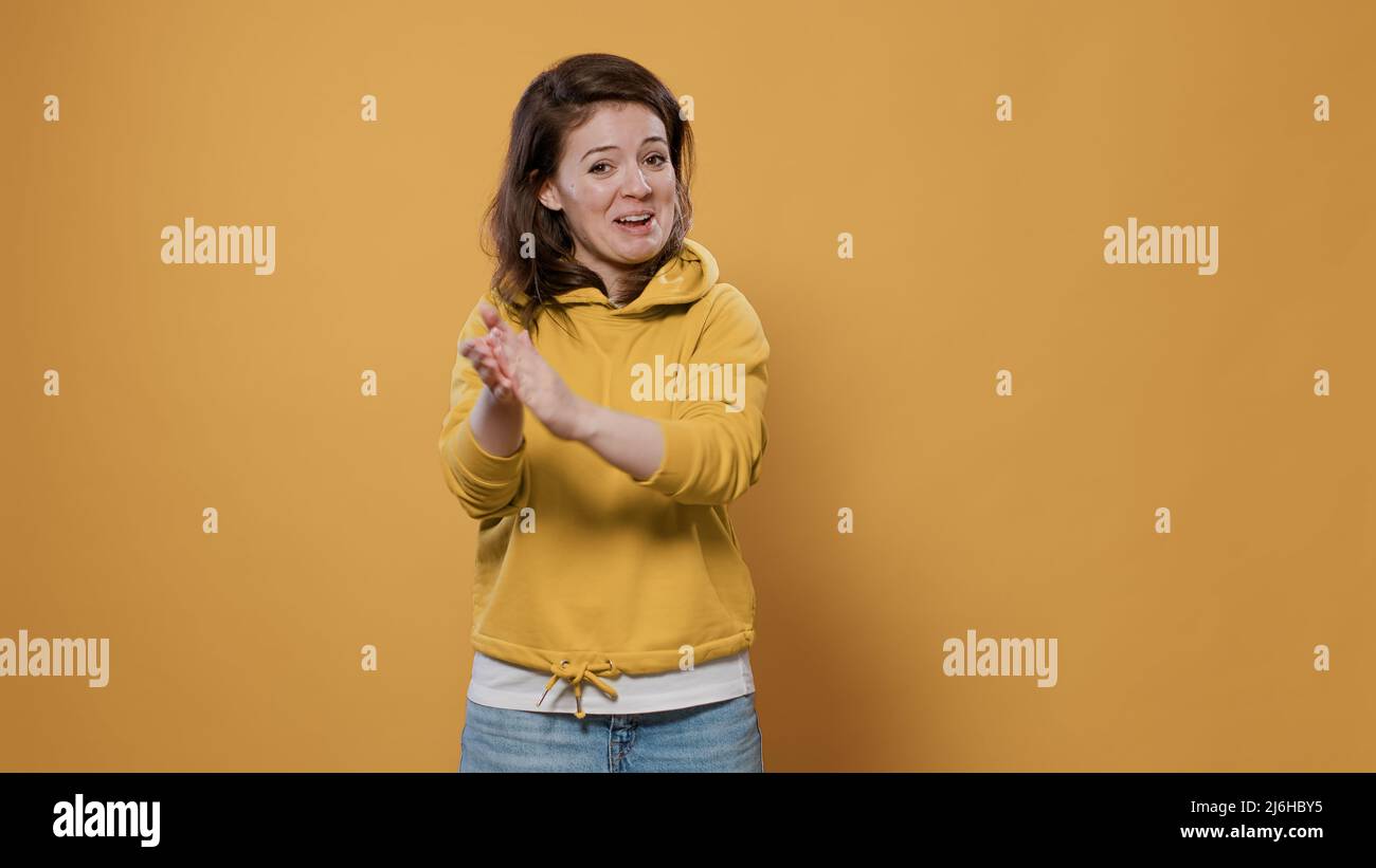 Happy casual woman clapping being supportive wearing hoodie over yellow ...