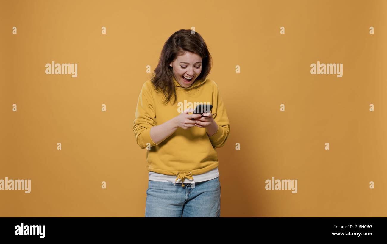 Portrait of casual woman holding smartphone texting having funny online conversation on social ...