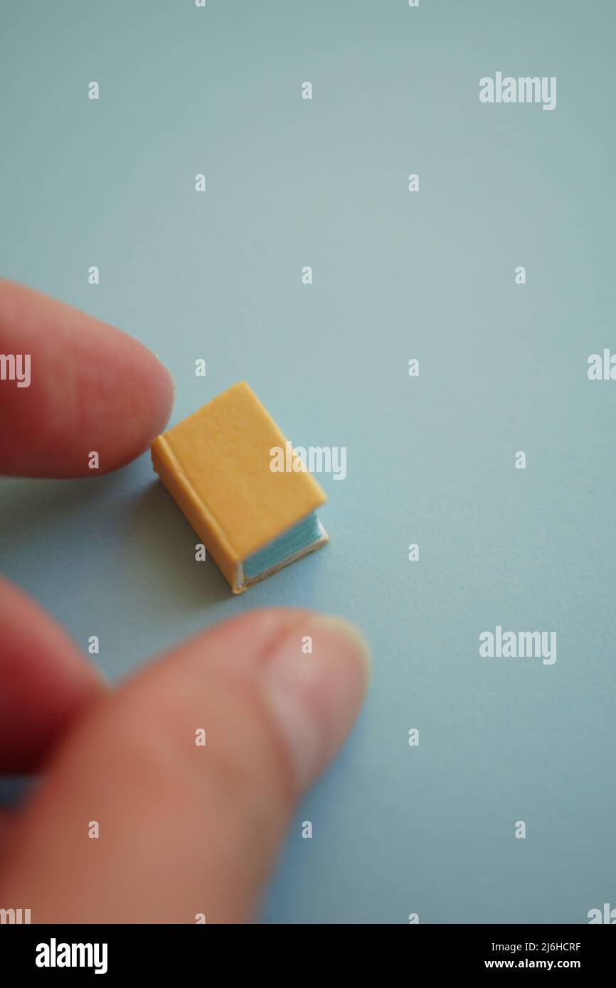 Miniature book and female fingers, mini book notepad craft on the blue ...