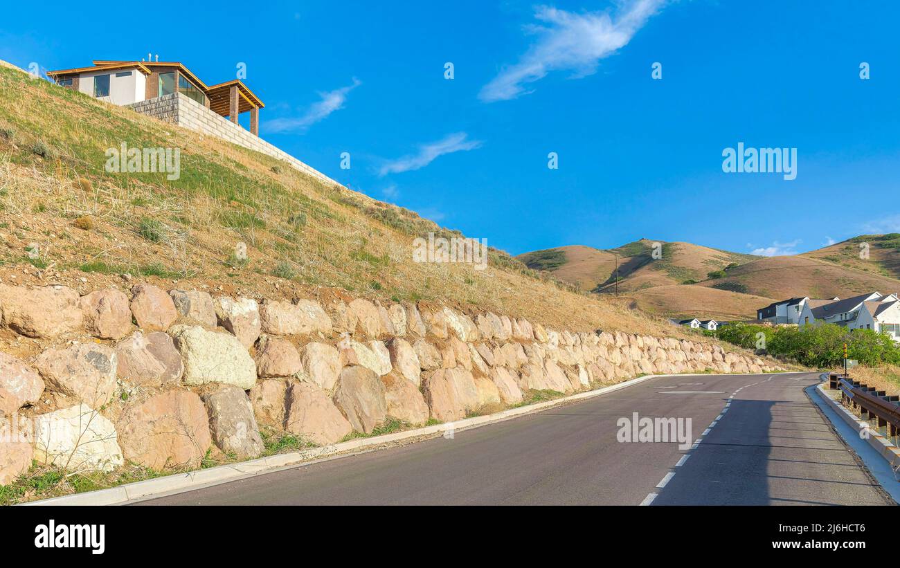 Panorama Paved road with roadside barrier beside the retaining wall of ...