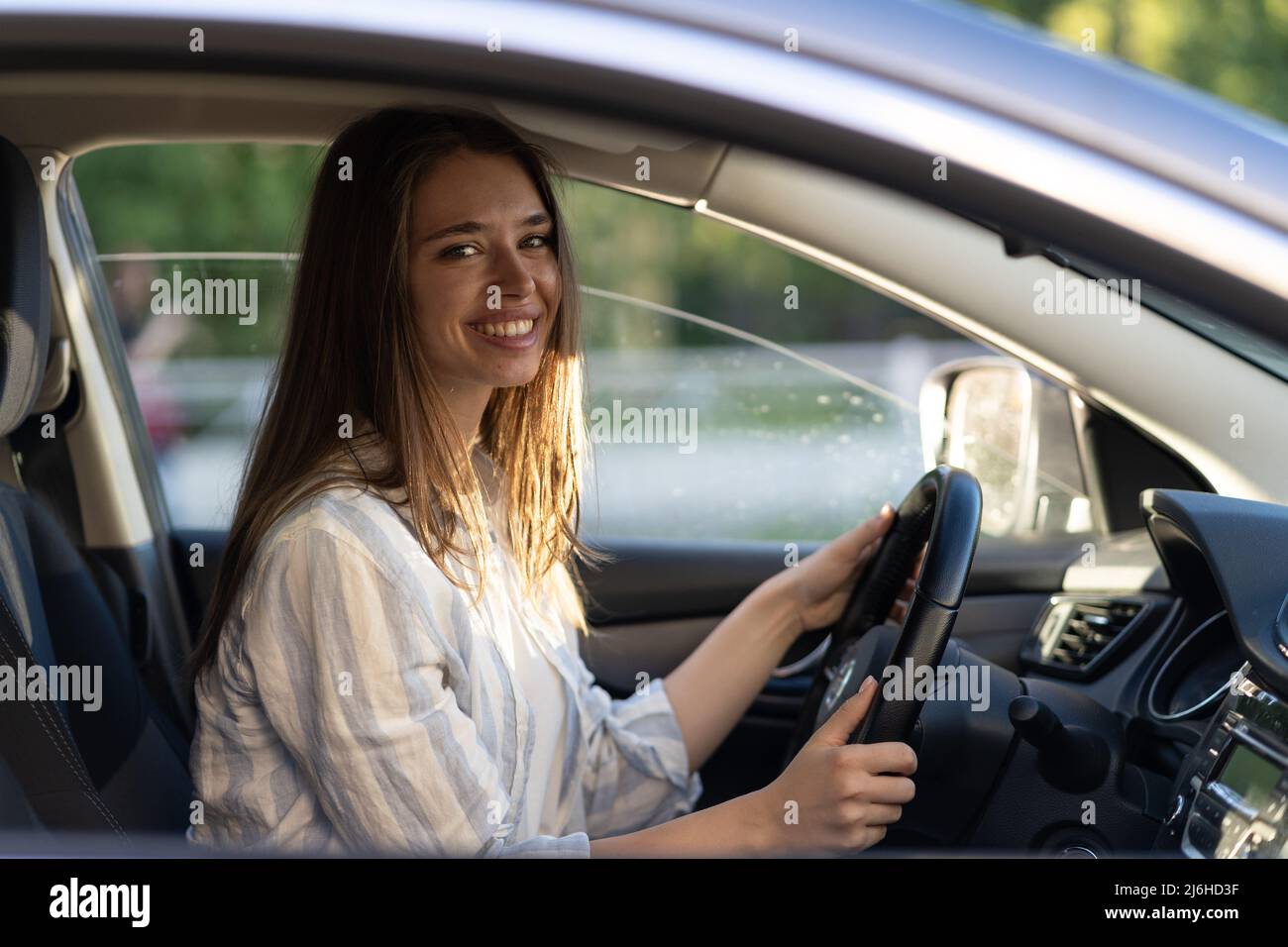 Young girl sit at driver seat in new car smiling hold hands on wheel ...