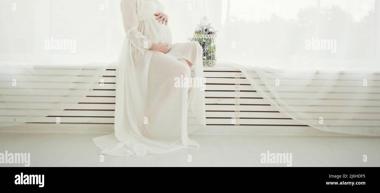 pregnant woman in dress sitting near the window. Concepts of pregnancy ...