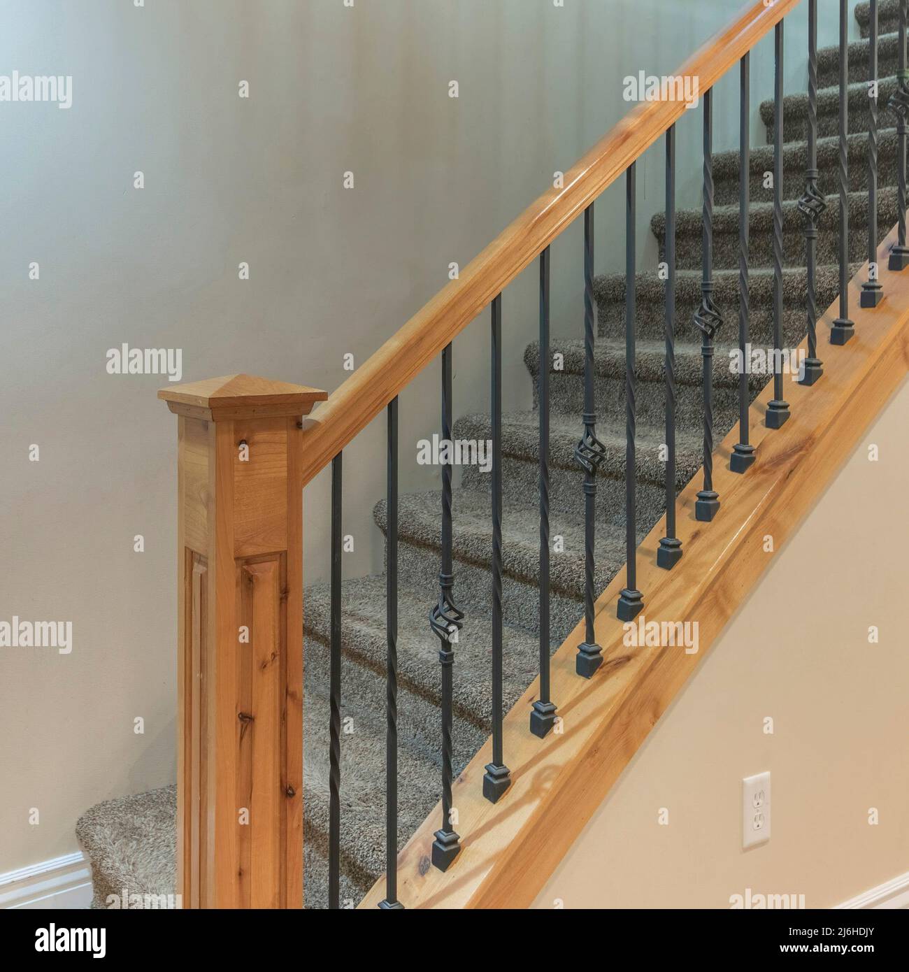Square Carpeted stairs with wooden handrailing and wrought iron ...