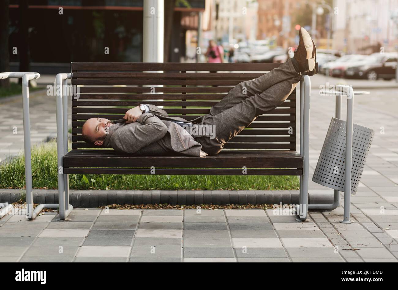 tired man in a suit is lying on a bench. sleeping, relaxing concept ...