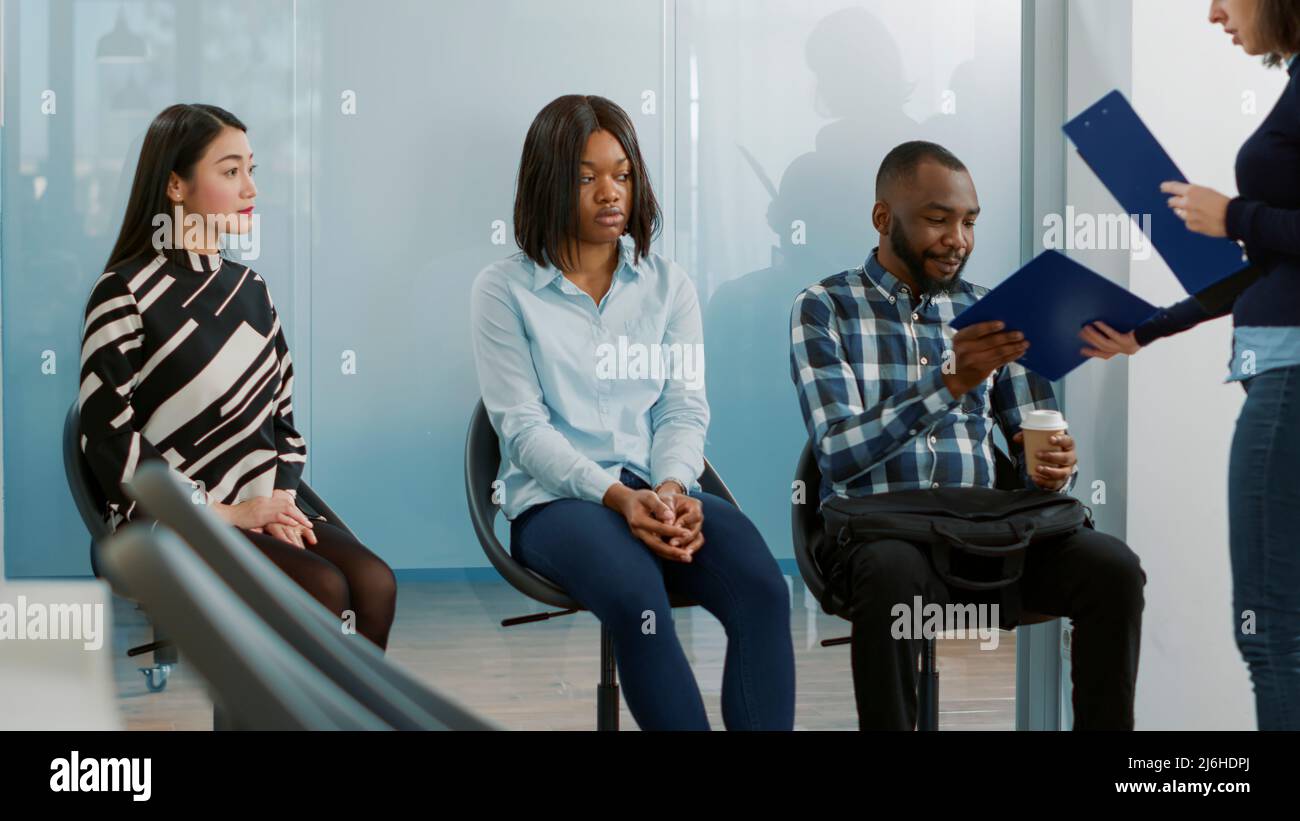 HR employee giving cv files to stressed candidates in lobby, waiting in ...